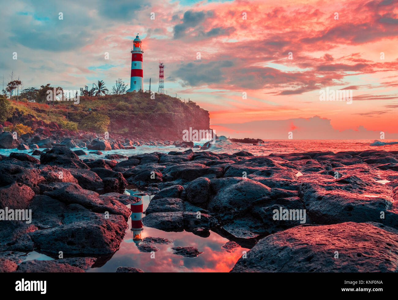 Lighthouse by sunset on the coast of mauritius with a red orange sky ...