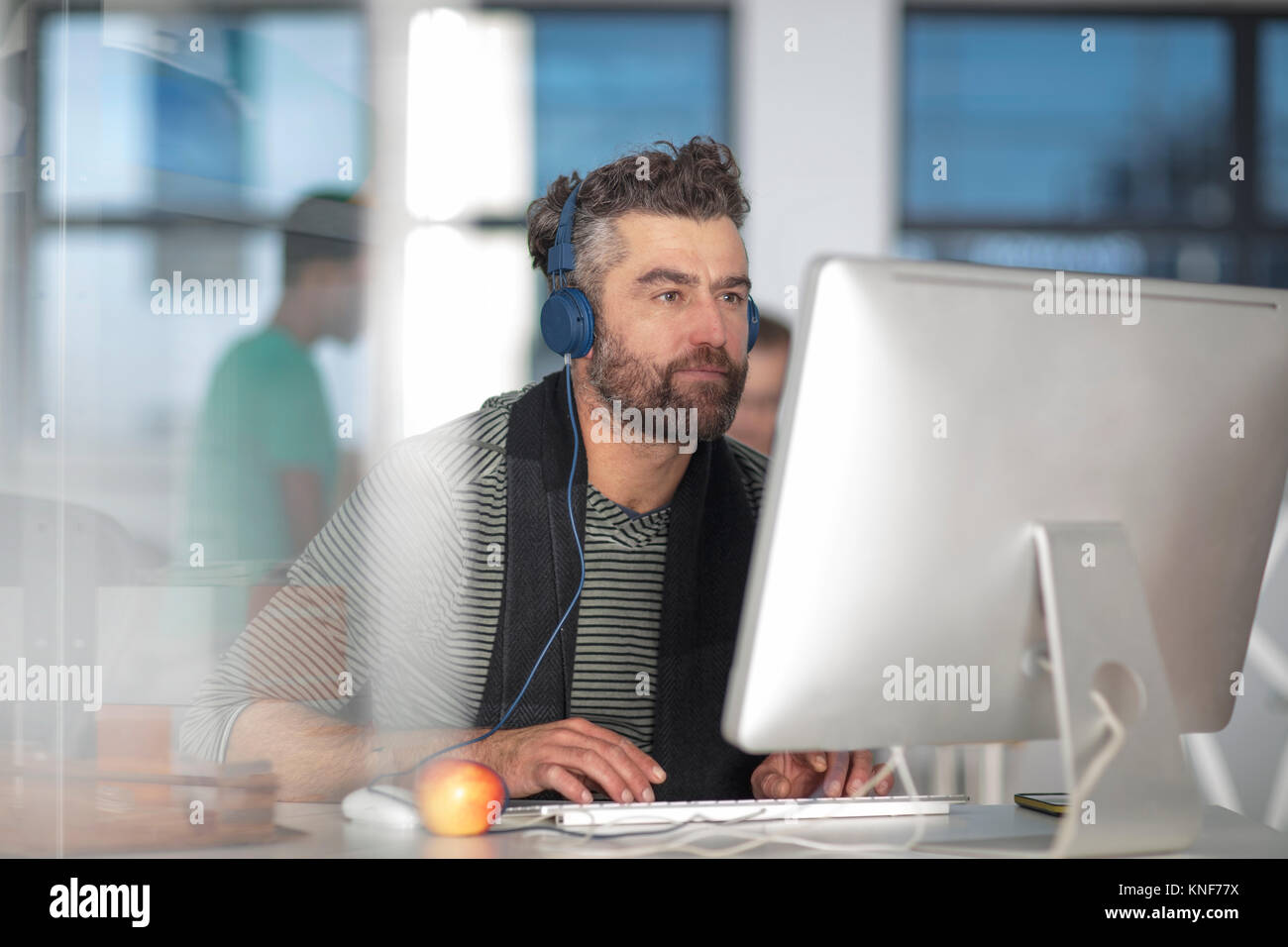 Man in office wearing headphones, using computer Stock Photo - Alamy