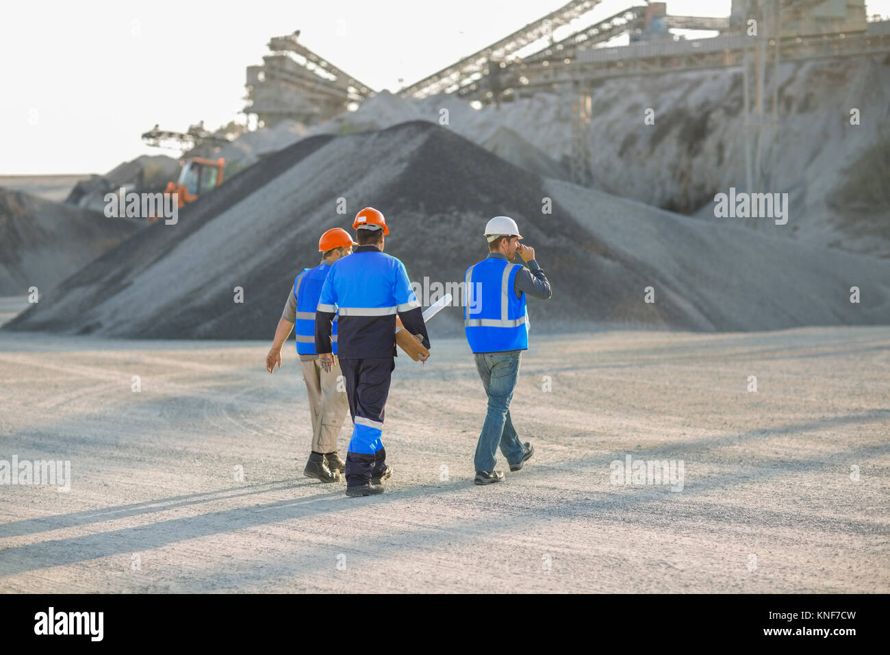 Three quarry workers, walking across quarry, rear view Stock Photo - Alamy