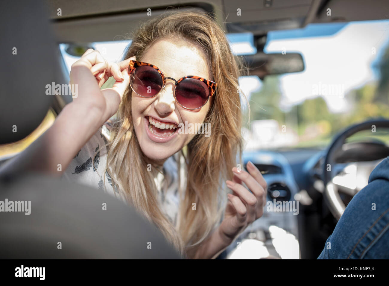 Young woman in car, looking over shoulder, laughing Stock Photo - Alamy