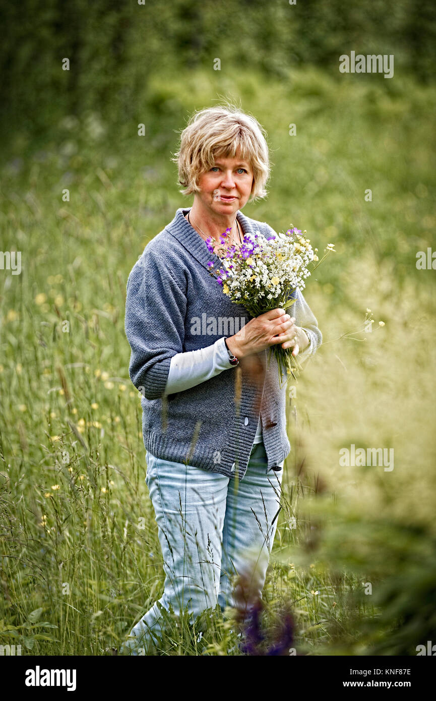 Woman picking flowers in a flower field Stock Photo - Alamy