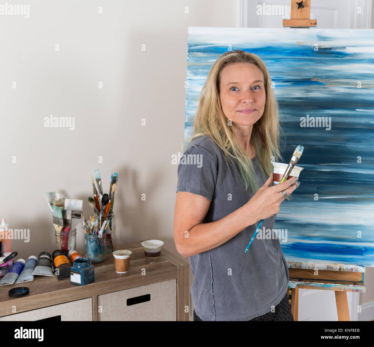 Portrait of mature female artist with abstract canvas in studio Stock ...