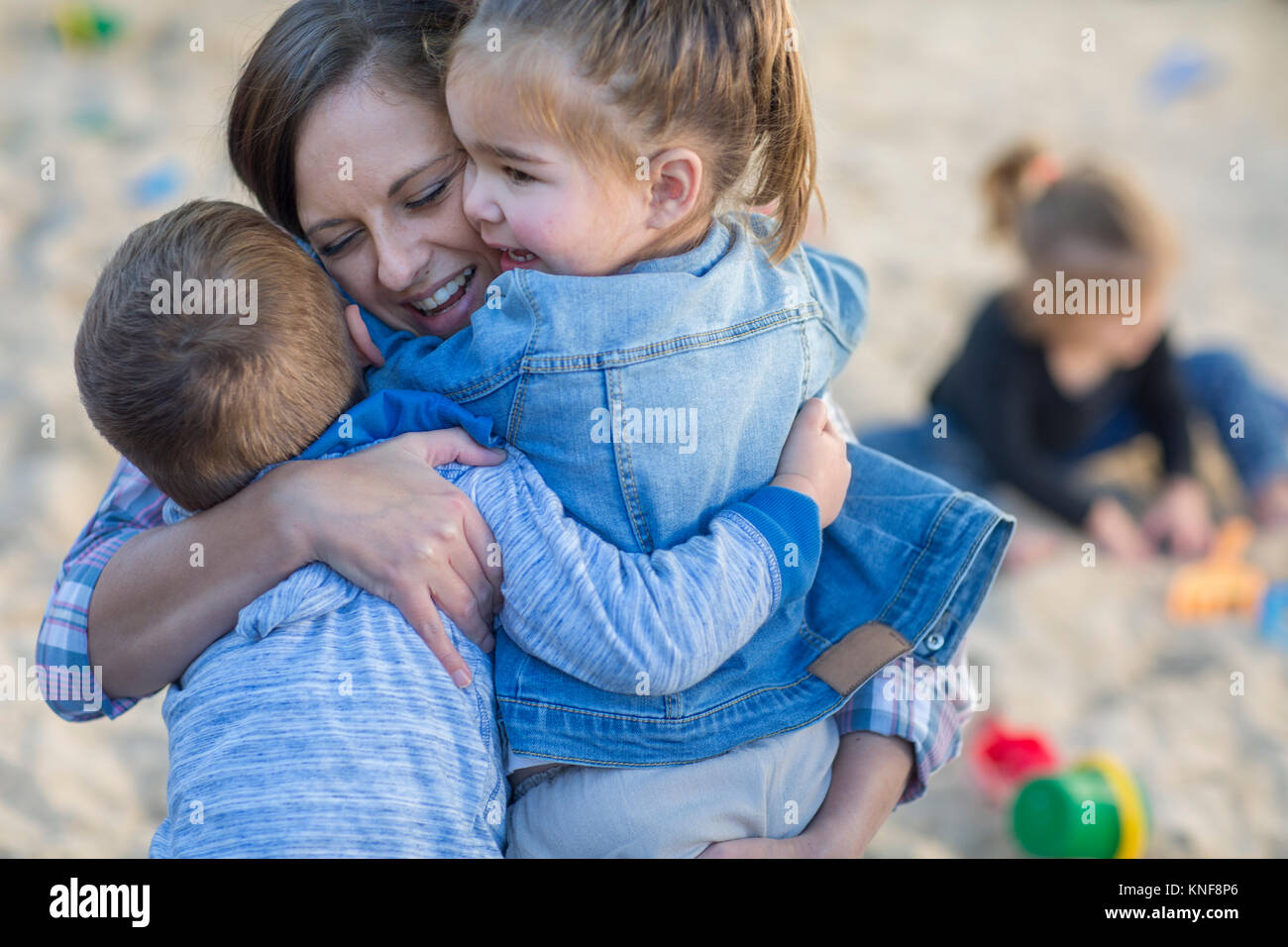 Mid adult woman hugging two young children Stock Photo - Alamy
