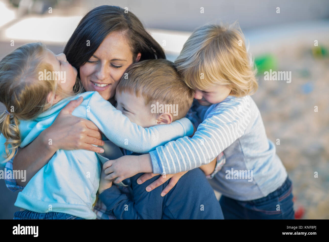 Mid adult woman hugging three young children Stock Photo - Alamy