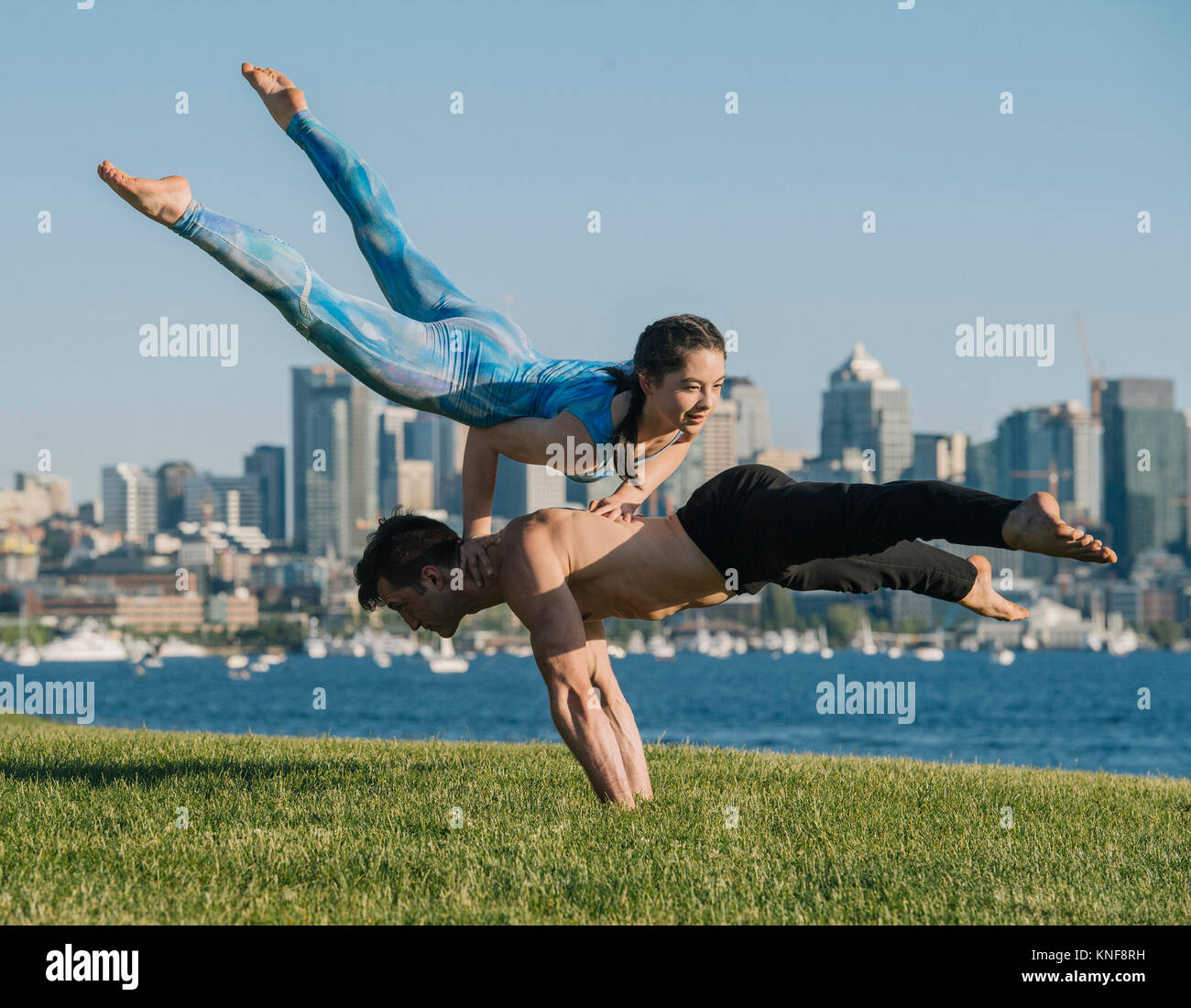 Teenage girl and young man, outdoors, man balancing on hands, girl ...