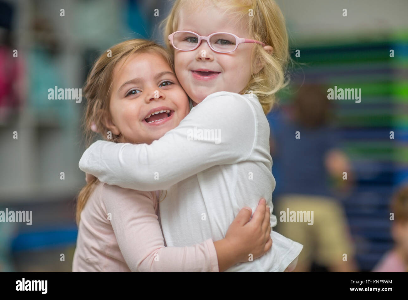 Portrait of two young girls in classroom, hugging Stock Photo - Alamy