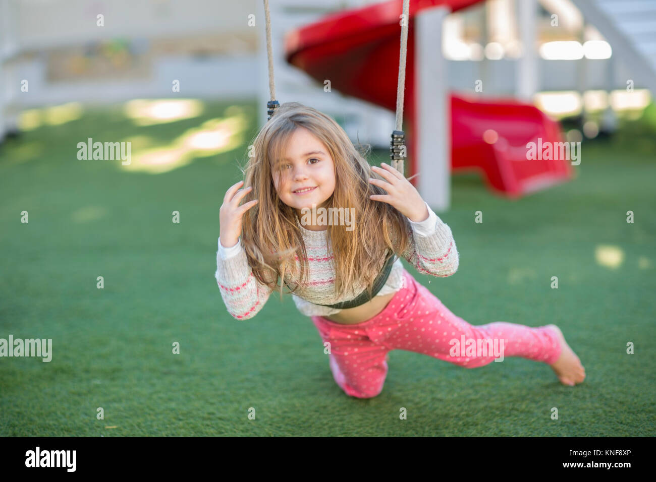 Girl at preschool, portrait lying on swing in garden Stock Photo - Alamy