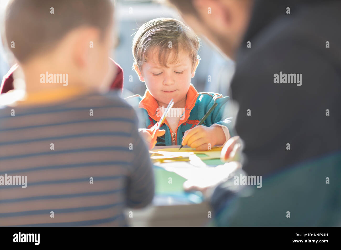 Group of people, outdoors, doing crafting activity, focus on young boy ...