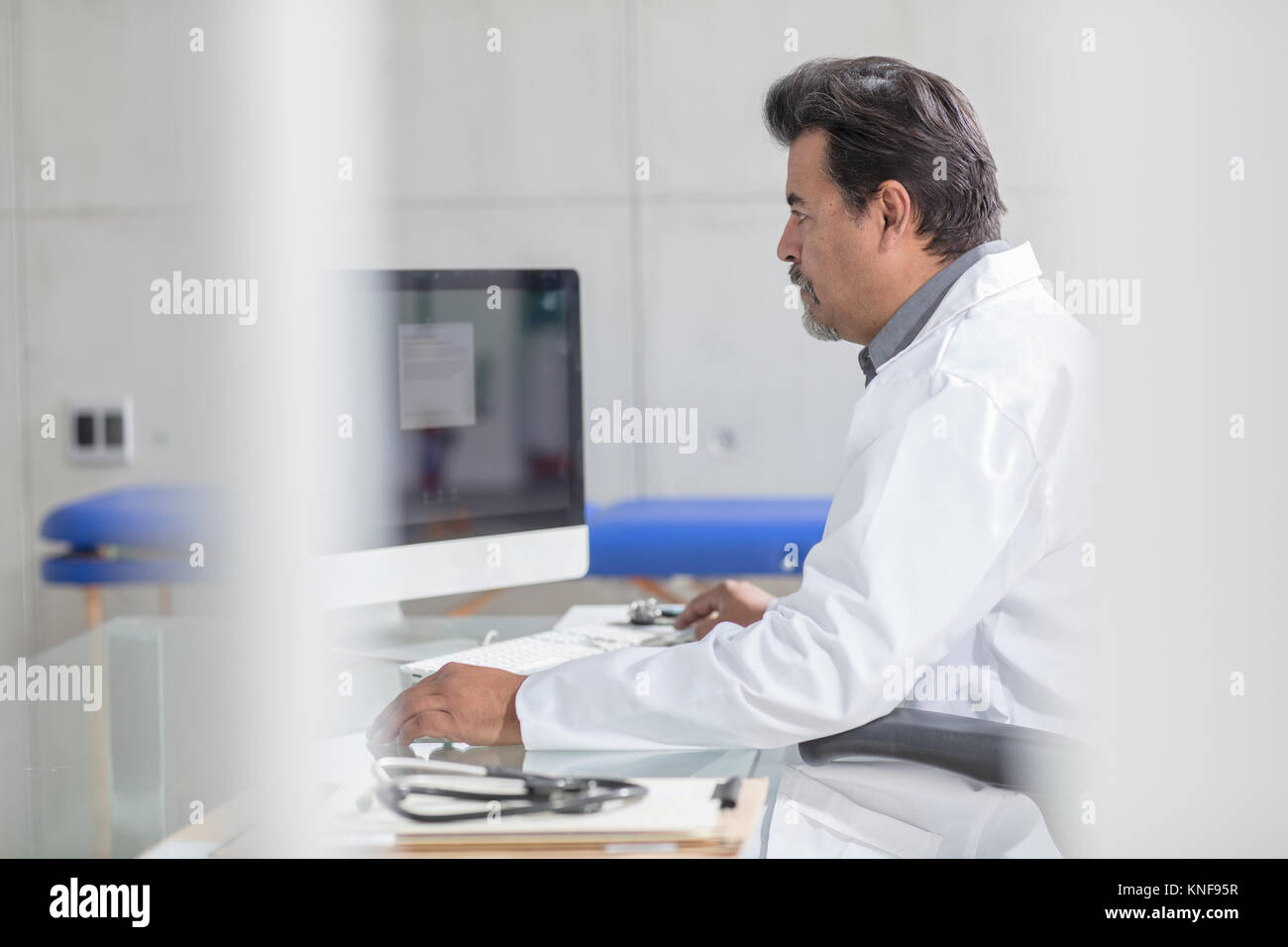 Male doctor working at computer Stock Photo - Alamy