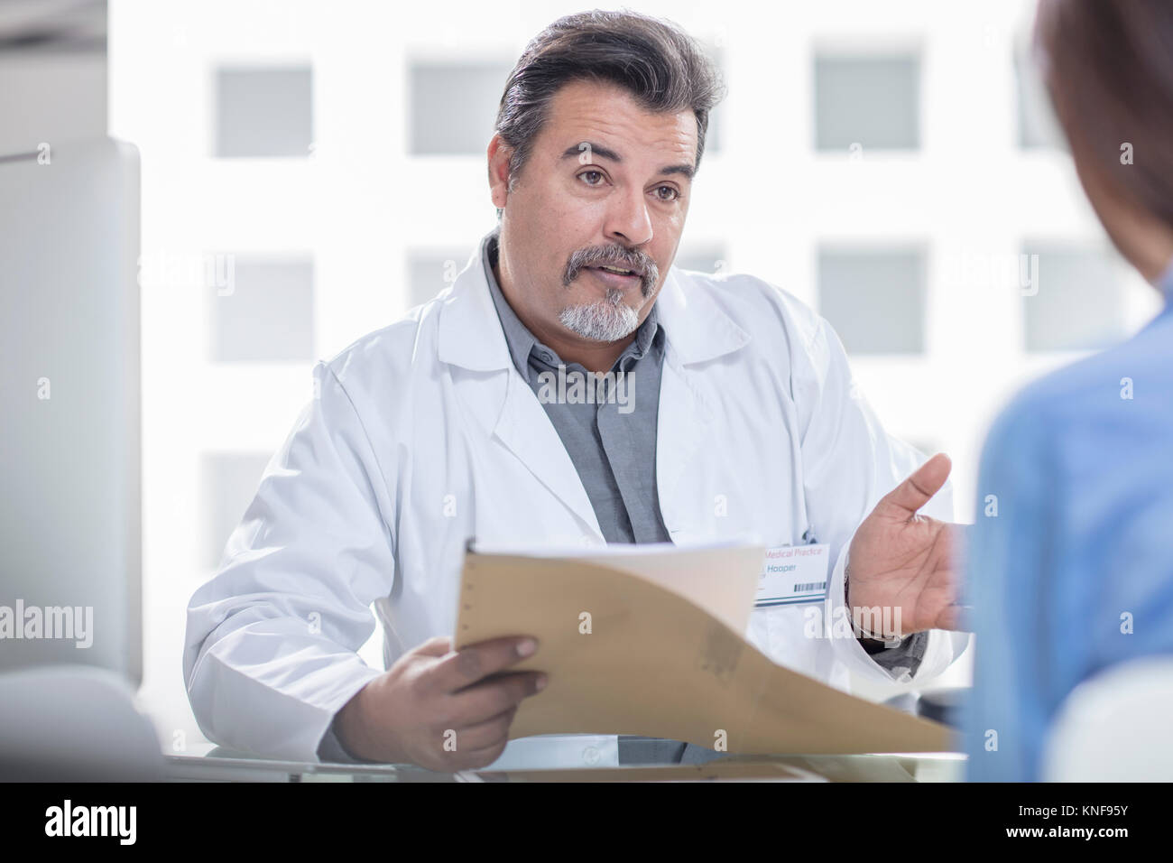 Male and female doctor sitting at table, having conversation Stock ...