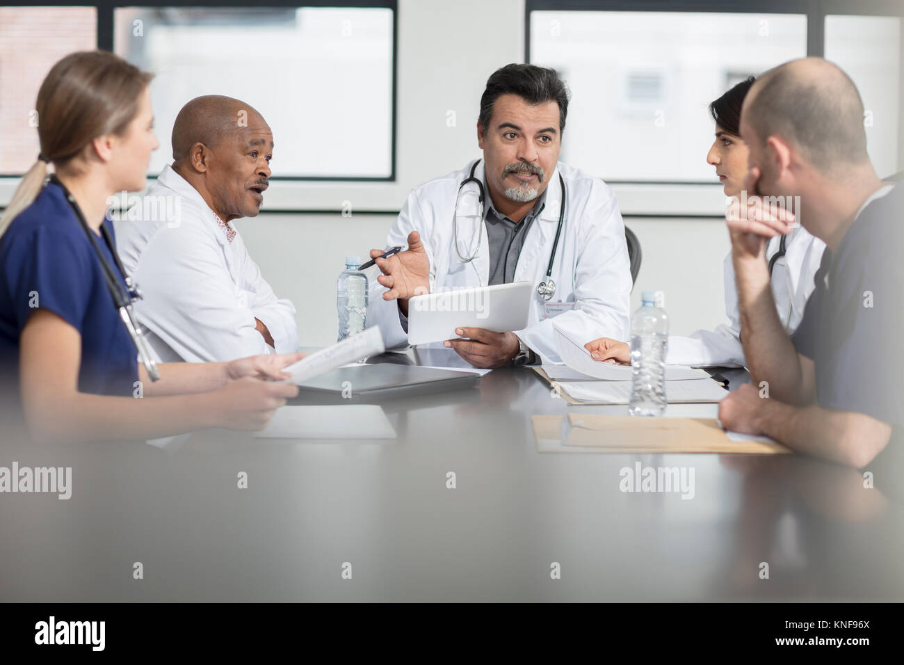 Group of doctors sitting at table, having discussion Stock Photo - Alamy