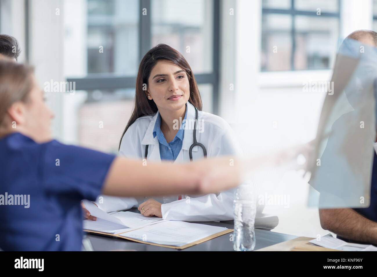 Group of doctors sitting at table, having discussion Stock Photo - Alamy
