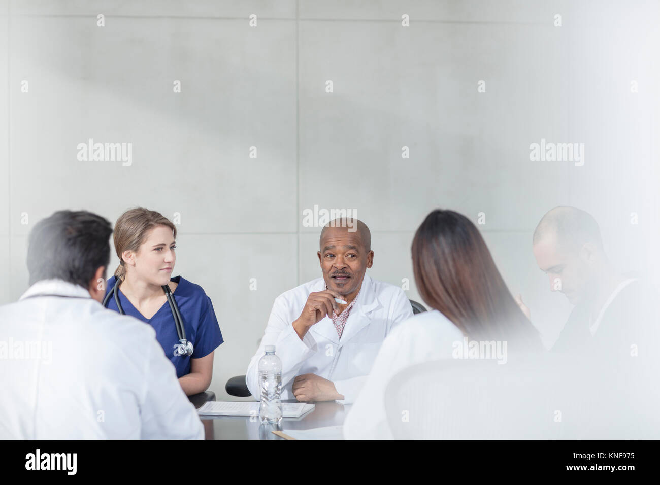 Group of doctors sitting at table, having discussion Stock Photo - Alamy