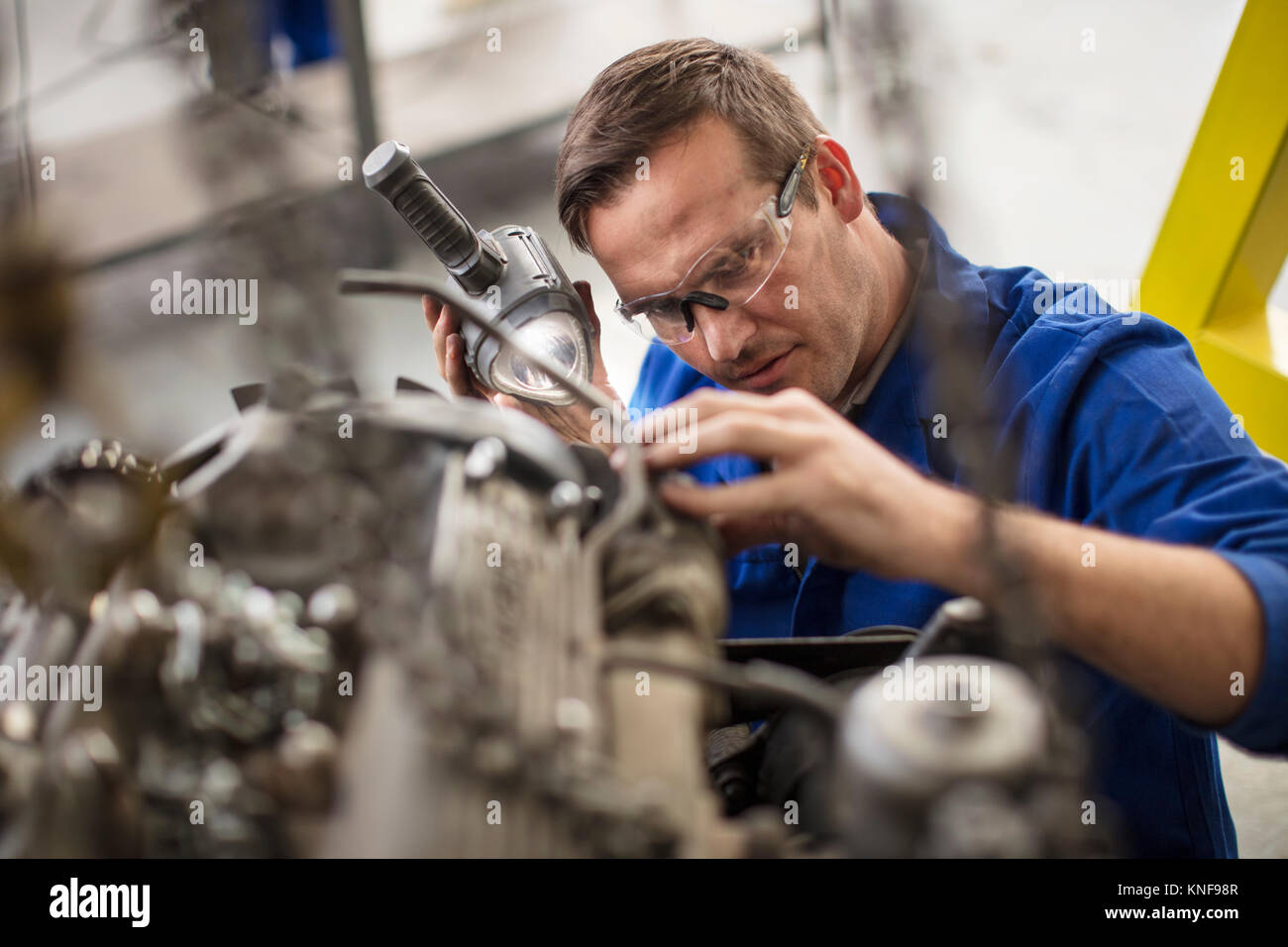 Car mechanic inspecting car part in repair garage Stock Photo - Alamy
