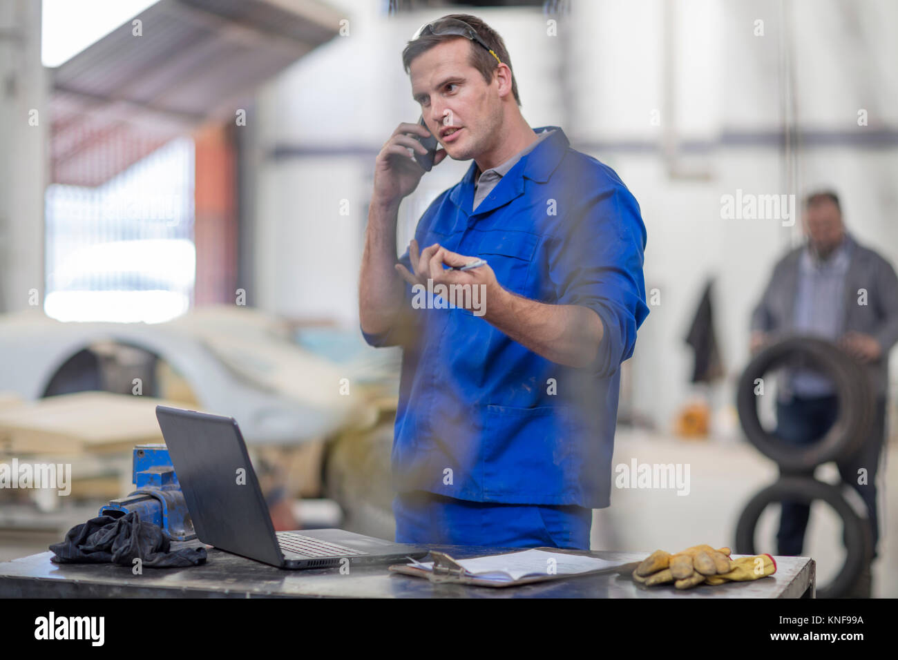 Car mechanic making smartphone call in repair garage Stock Photo - Alamy