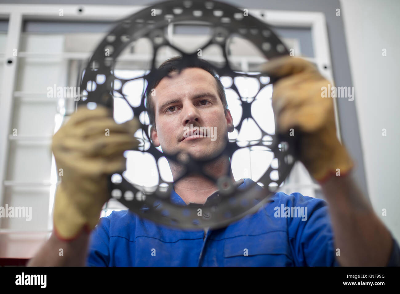 Car mechanic inspecting circular car part in repair garage Stock Photo ...