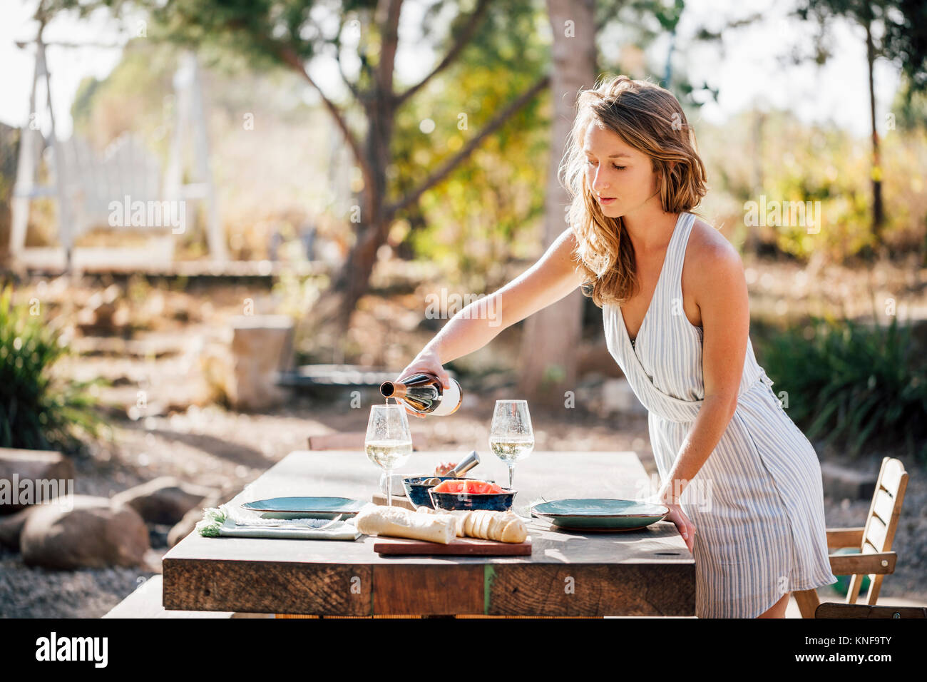 Young woman, outdoors, preparing dinner table, pouring wine Stock Photo ...