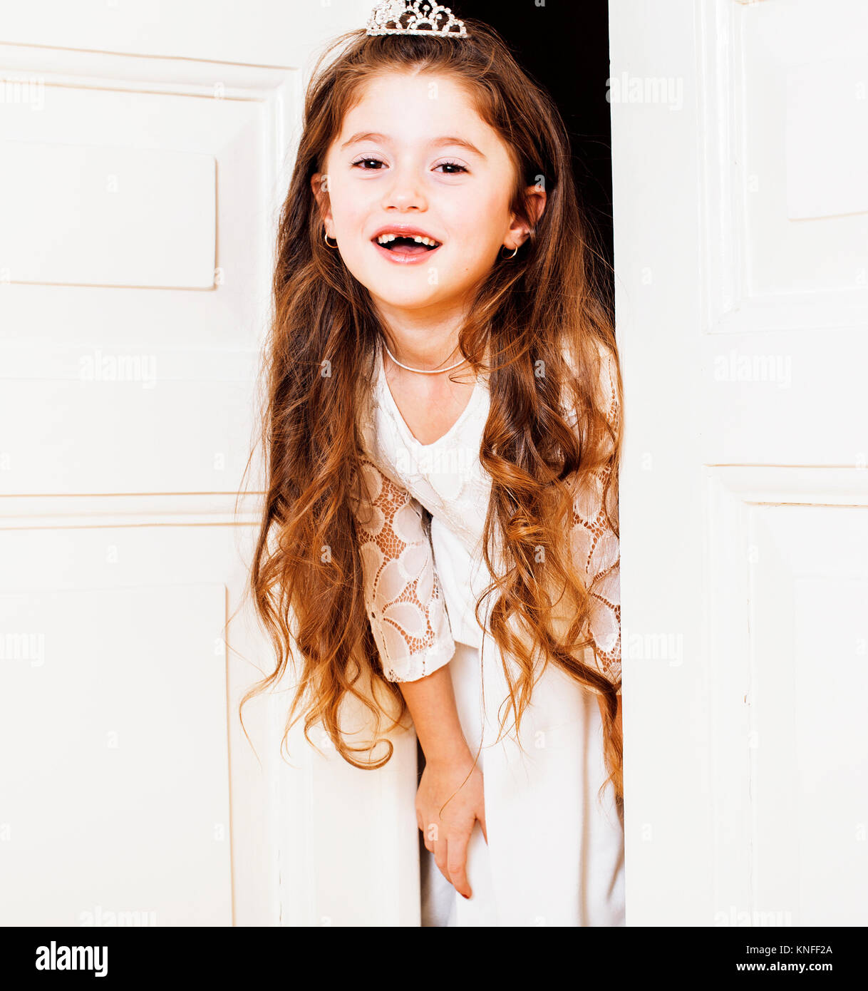 little cute girl at home, opening door well-dressed in white dress ...