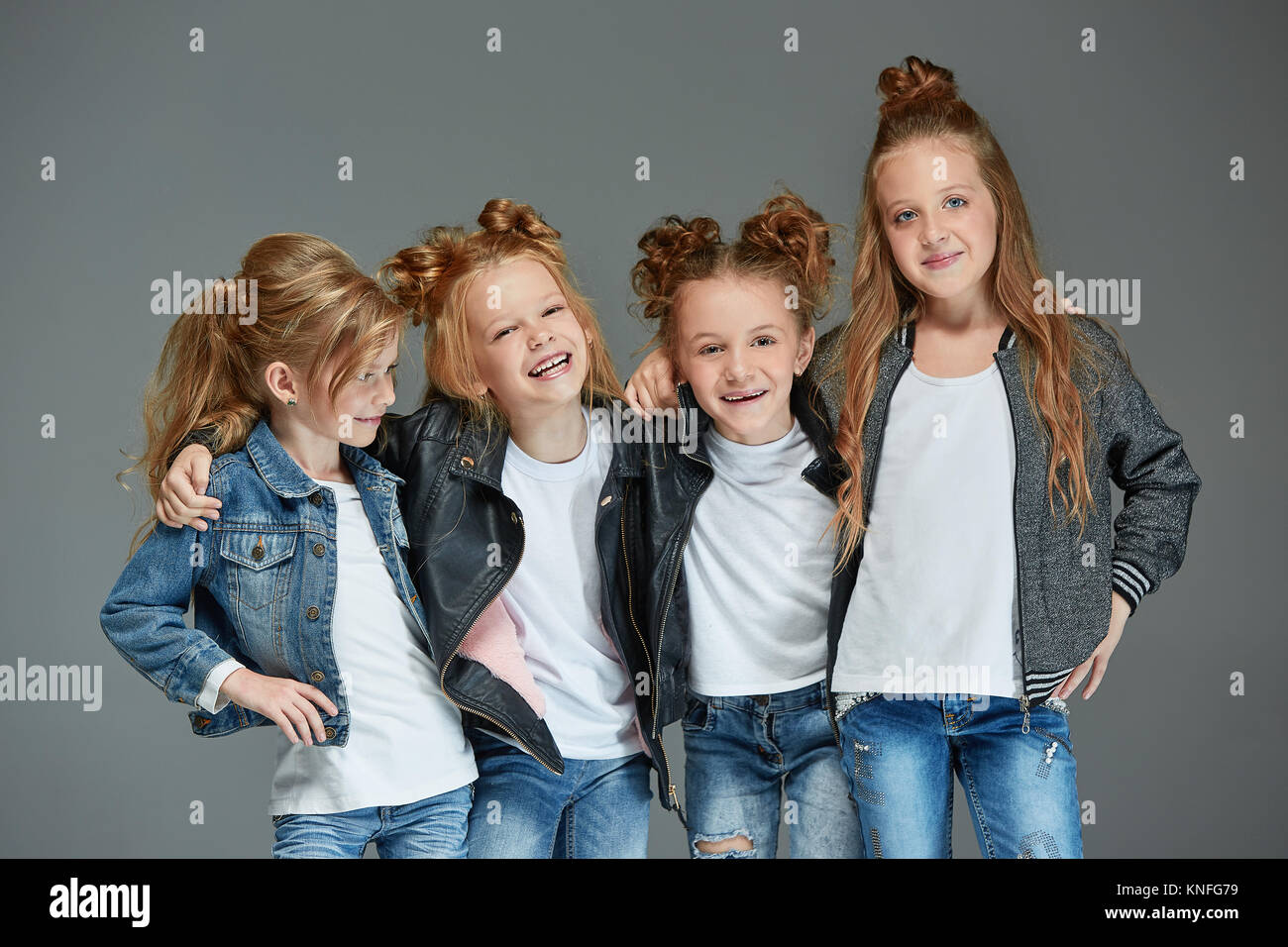 Young girls posing together on gray studio background Stock Photo - Alamy