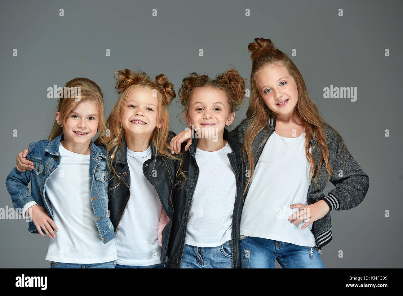 Young girls posing together on gray studio background Stock Photo - Alamy