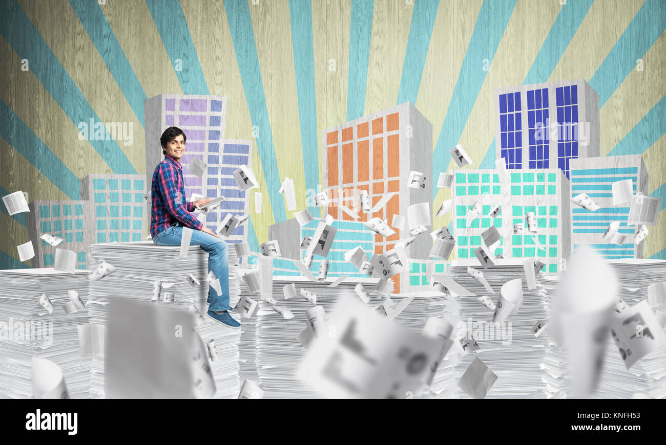 Young man sitting on pile of paper documents Stock Photo - Alamy