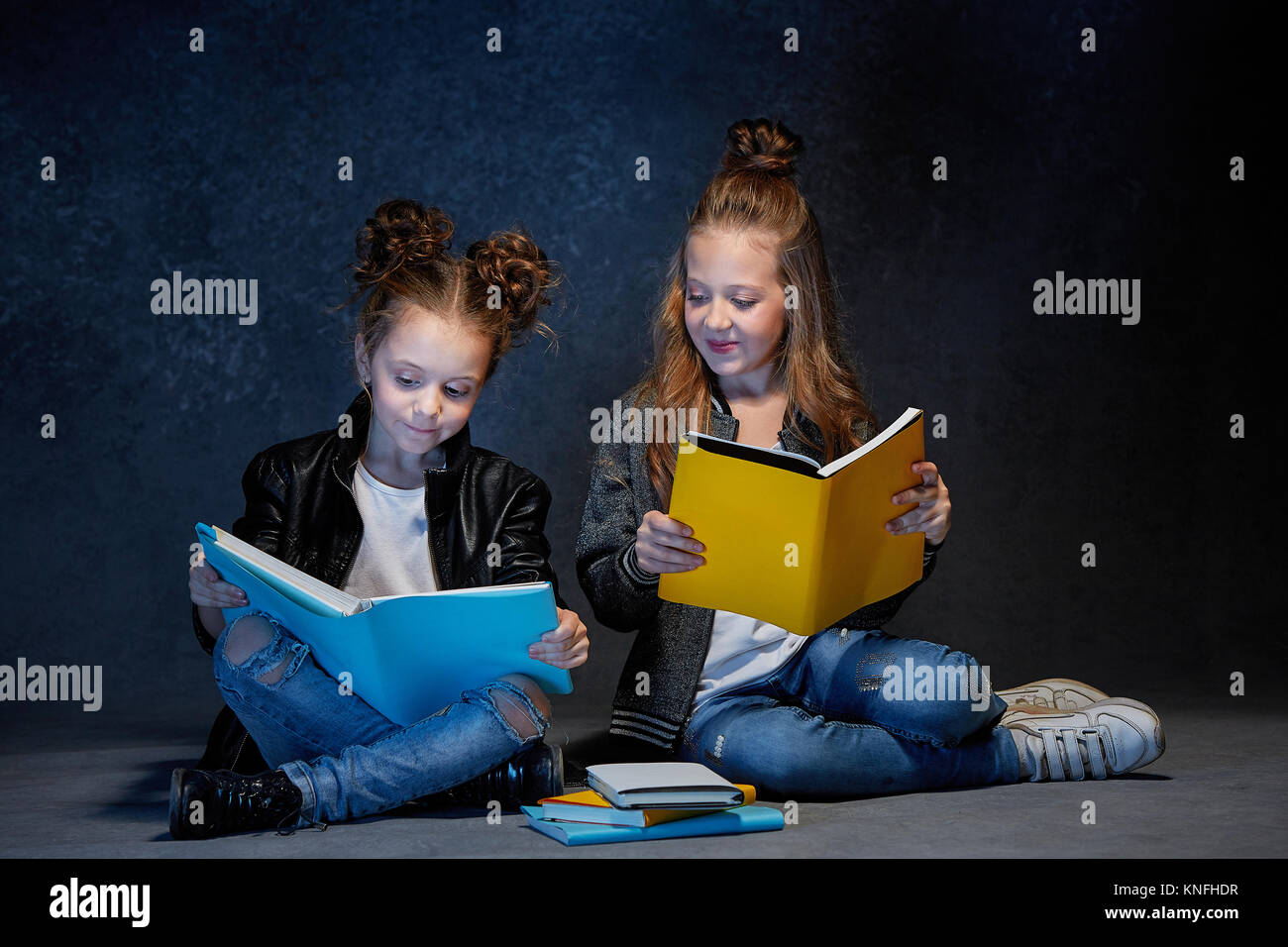Two kids reading the book at gray studio Stock Photo - Alamy