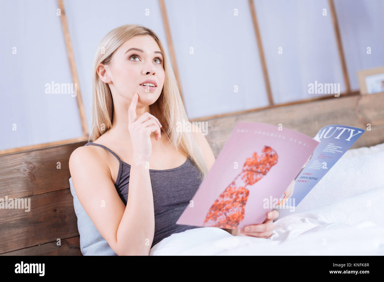 Charming young woman reading magazine in bed Stock Photo - Alamy