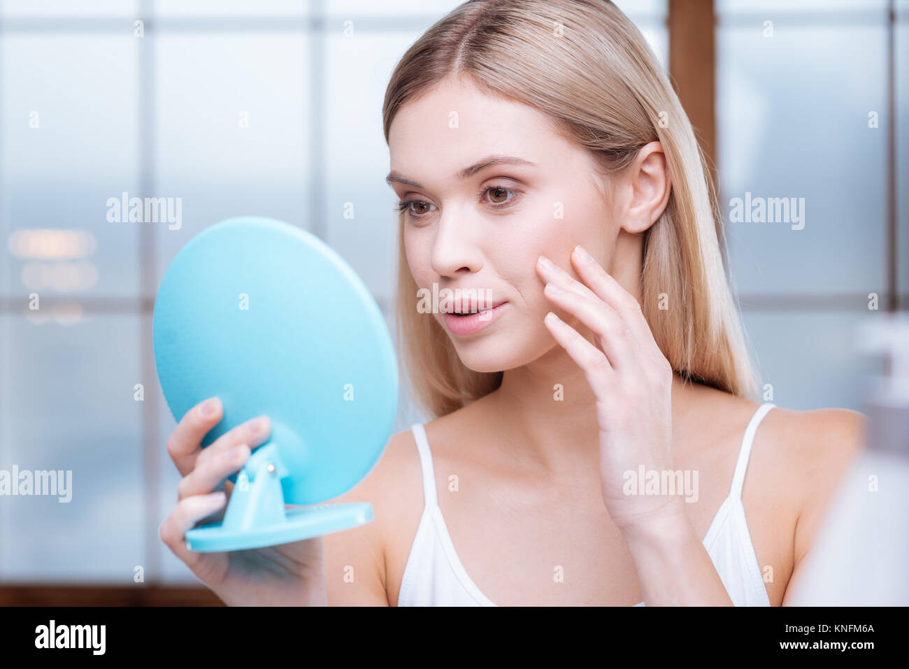 Beautiful woman checking her skin condition in the mirror Stock Photo ...