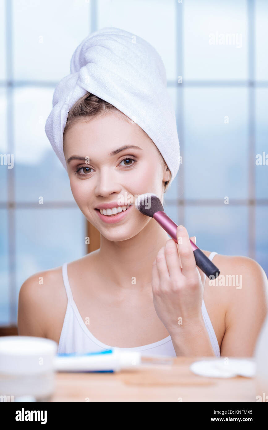 Cheerful woman applying powder and smiling Stock Photo - Alamy