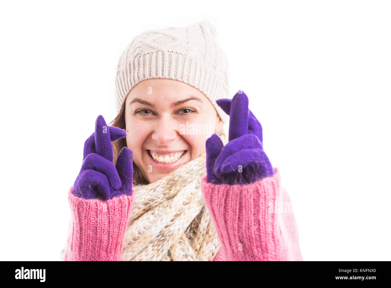 Woman wearing winter clothes making good luck gesture with fingers ...