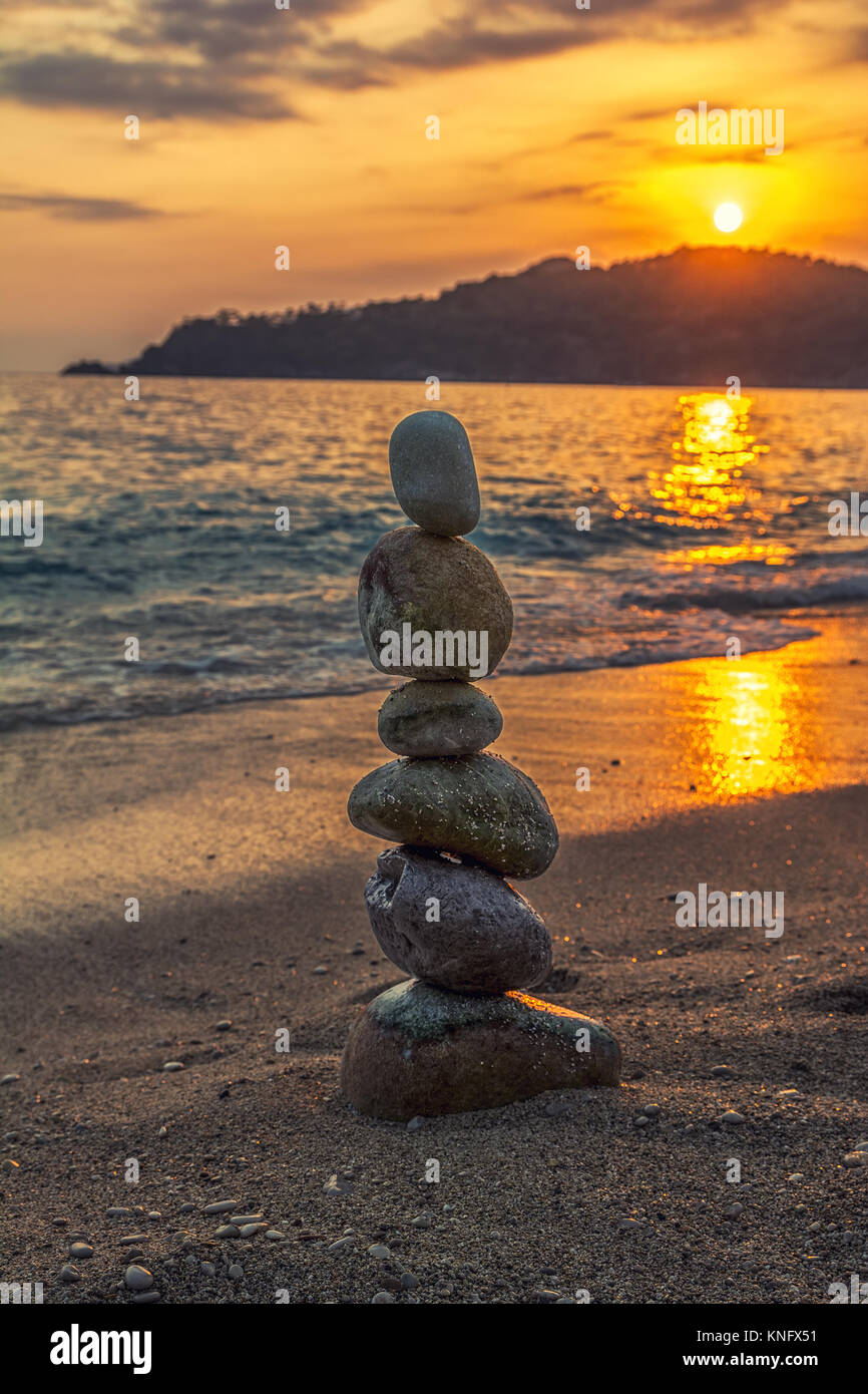 Zen stone tower on the beach. Sea and mountain on sunset background ...