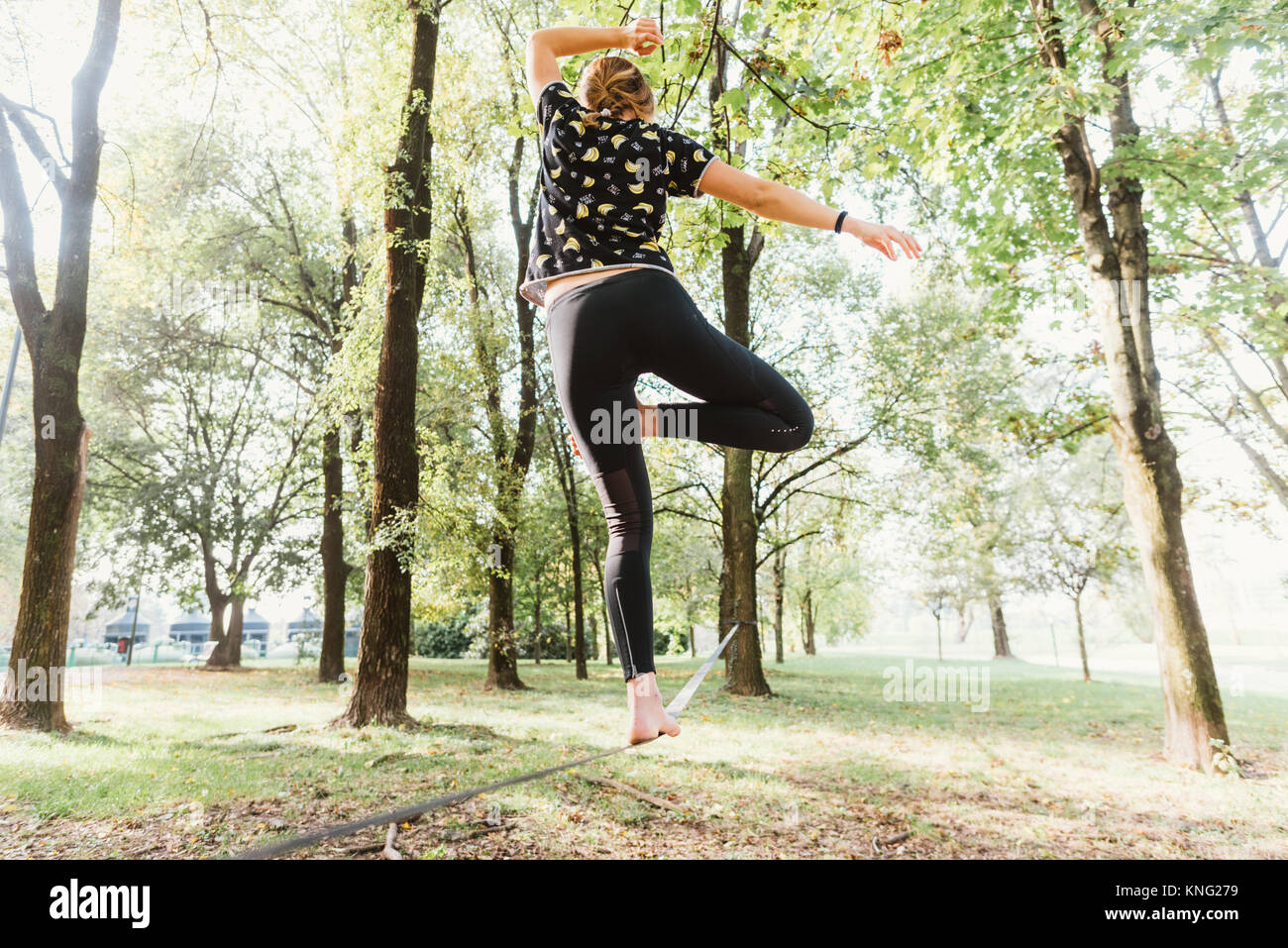 Woman balancing a tightrope or slackline outdoor in a city park in ...