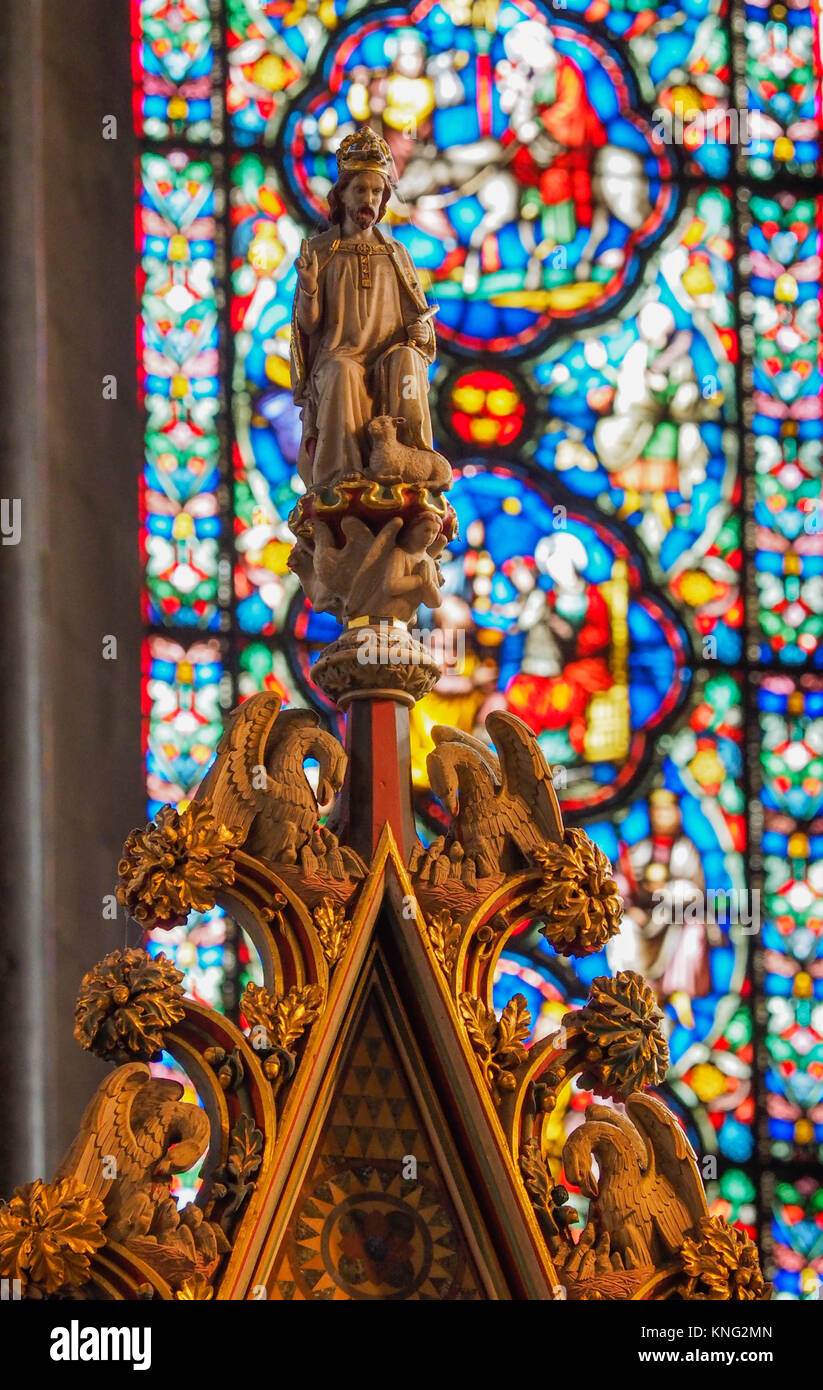 STAINED GLASS WINDOW OF ELY CATHEDRAL IN BACKGROUND WITH CARVED FIGURE ...