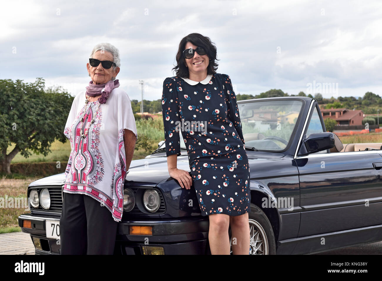 portrait of two women leaning on a car Stock Photo - Alamy