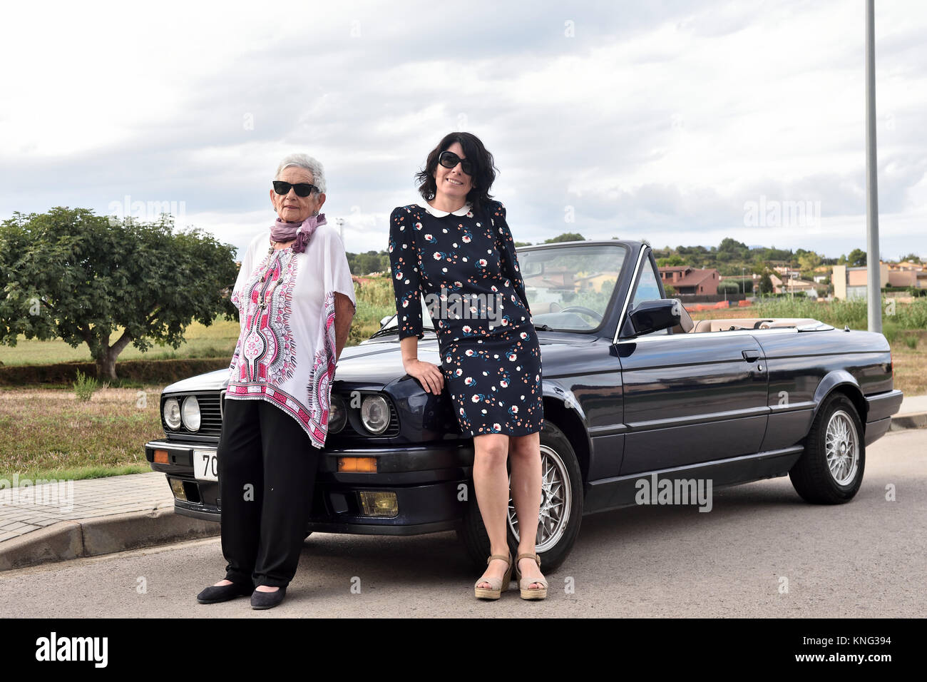 portrait of two women leaning on a car Stock Photo - Alamy