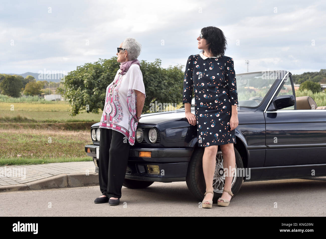 portrait of two women leaning on a car Stock Photo - Alamy