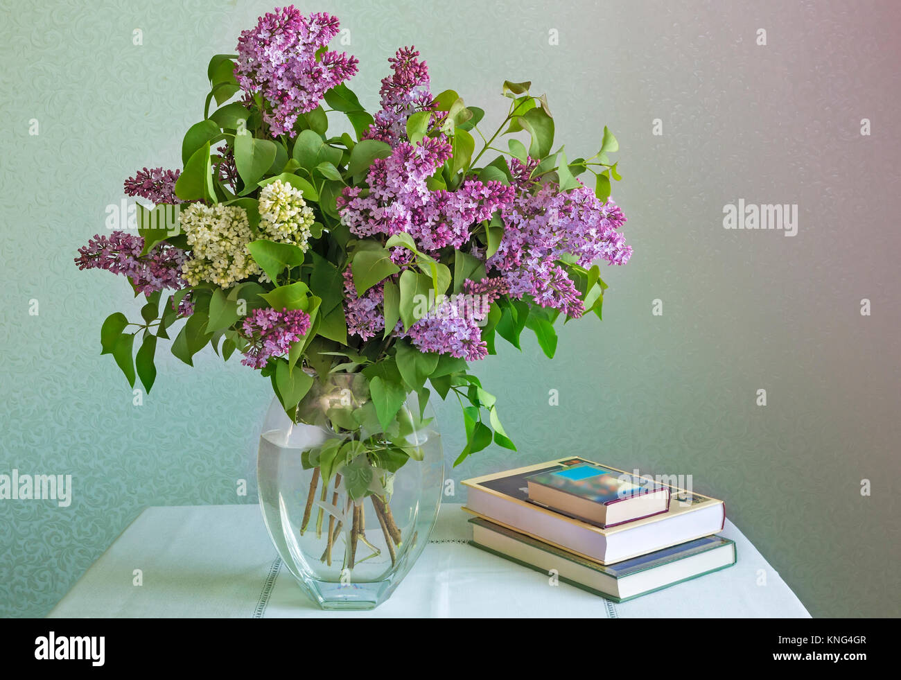 On the table is a vase with a beautiful bouquet of lilacs near are ...