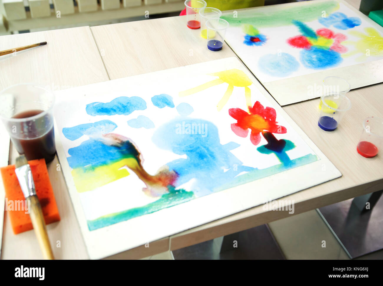 Children's drawings, brushes and paint left on the table Stock Photo ...