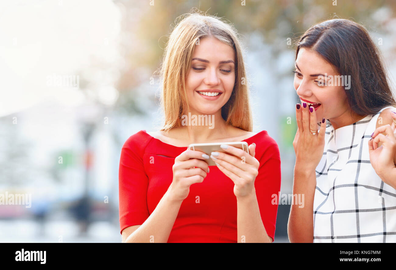 Woman shows on a mobile phone is something to his girlfriend. Happy ...