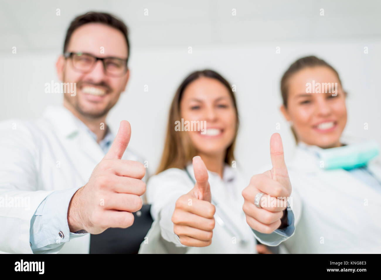 Friendly group of doctors with thumbs up by the white wall Stock Photo ...