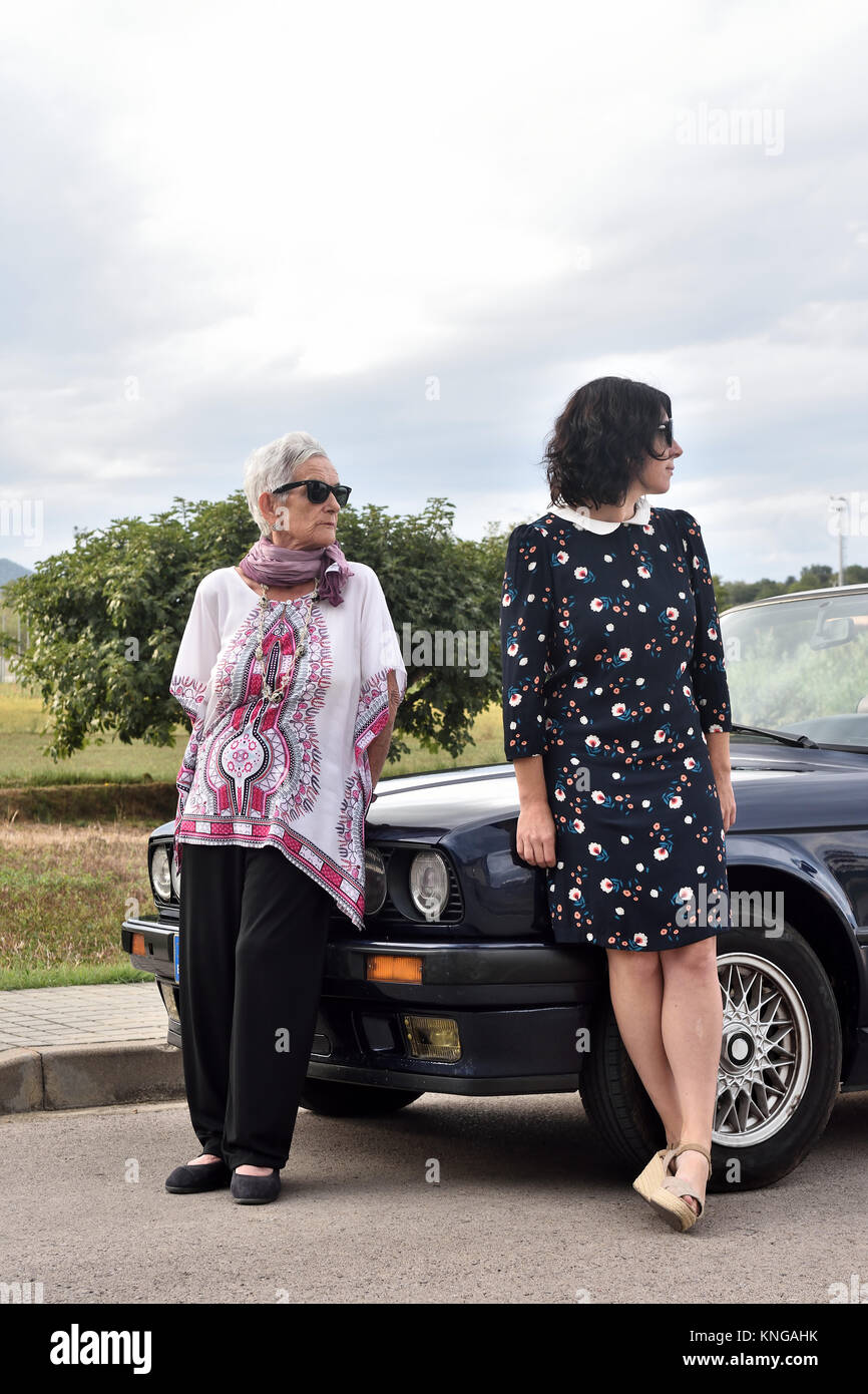 portrait of two women leaning on a car Stock Photo - Alamy