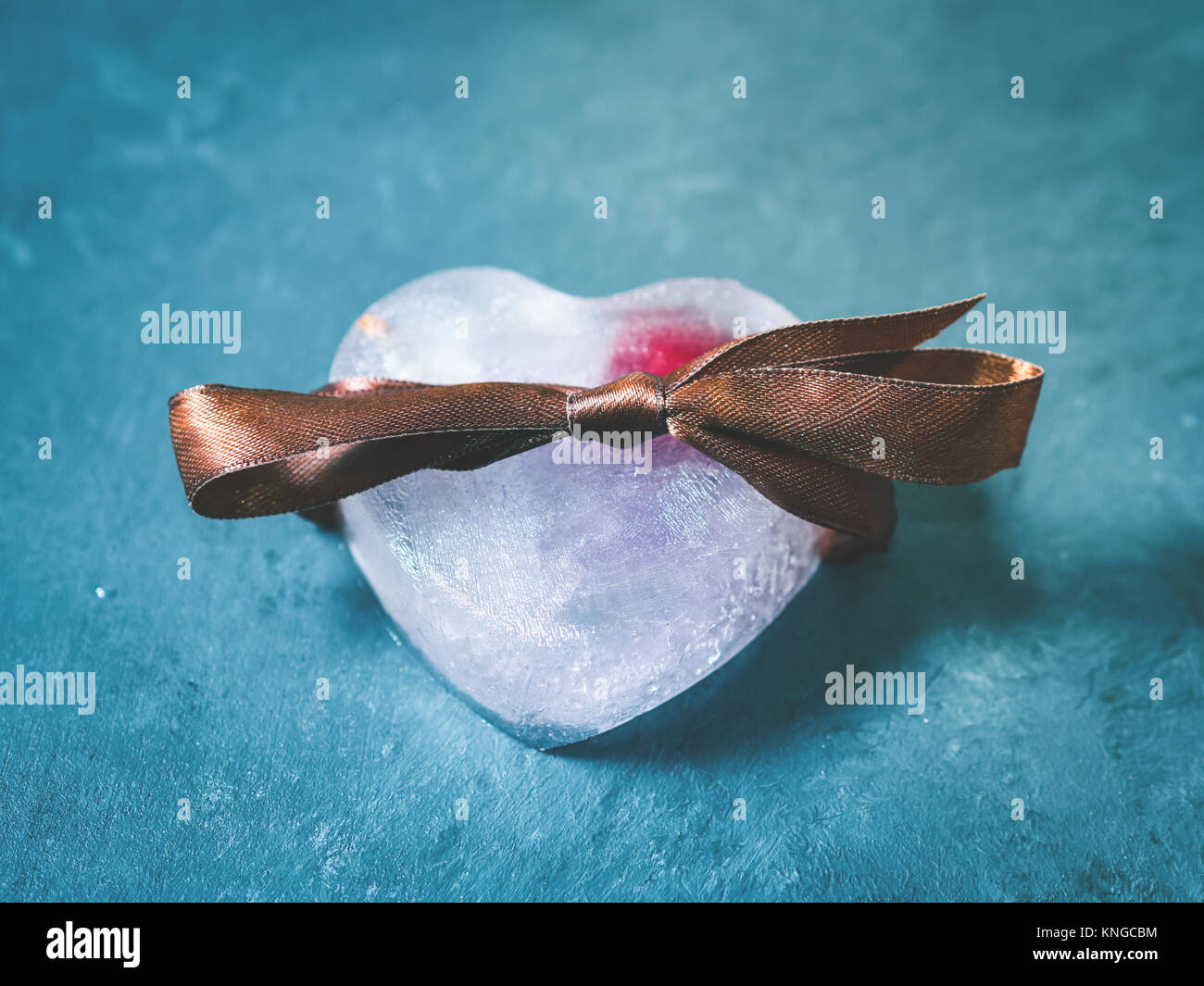 Heart shaped lavender syrup ice cubes with frozen cherry on blue ...