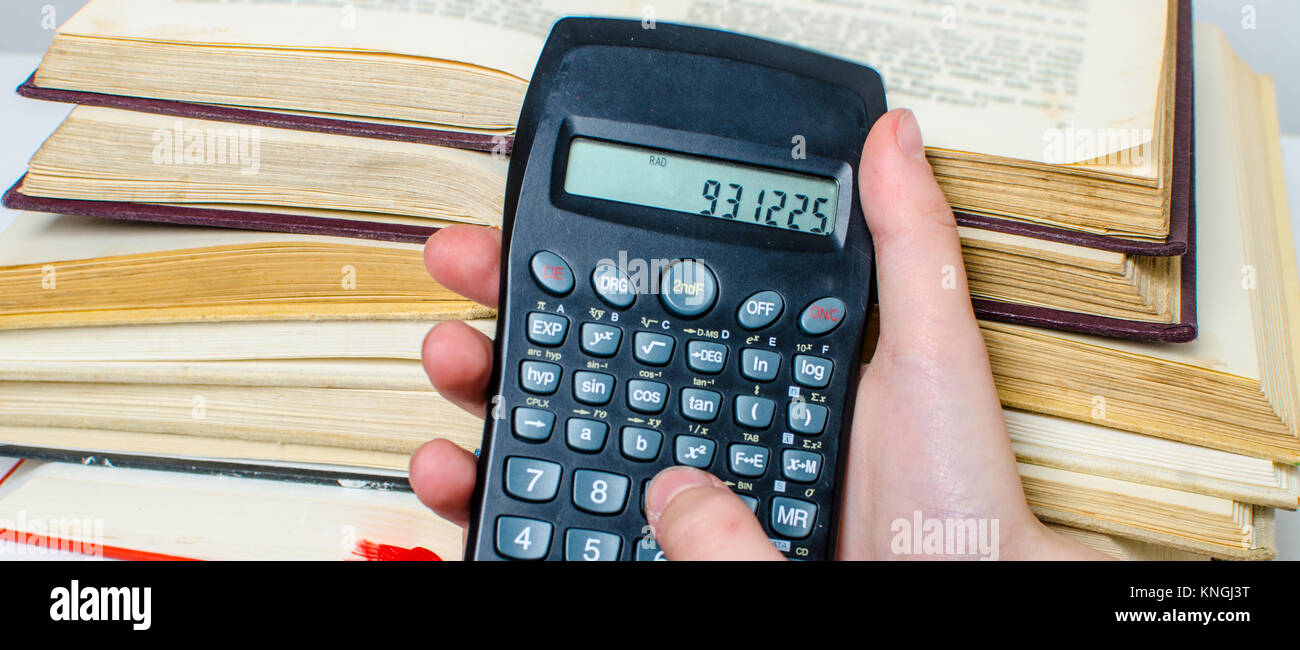 A pile of books and a calculator help in learning Stock Photo - Alamy