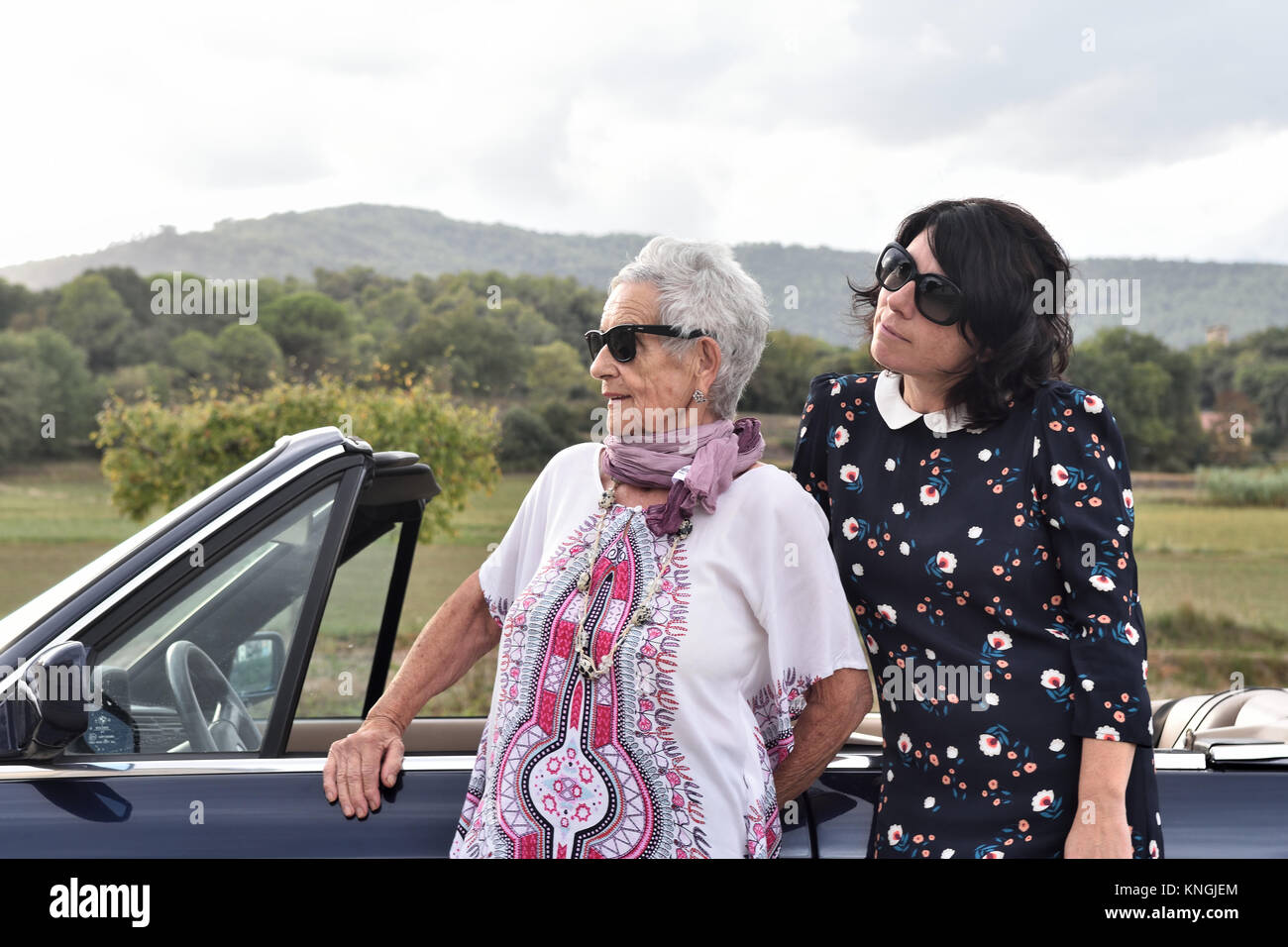 portrait of two women leaning on a car Stock Photo - Alamy