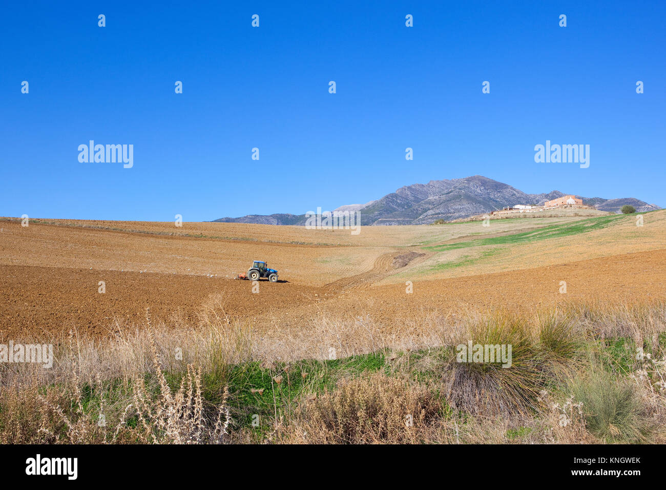 mountainous spanish farmland with a tractor plowing undulating arable ...