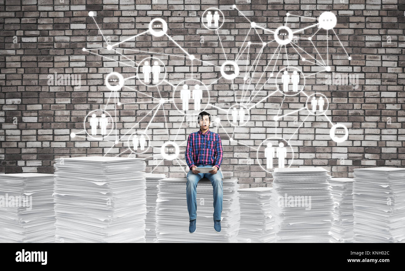 Attractive man sitting on pile of paper documents Stock Photo - Alamy