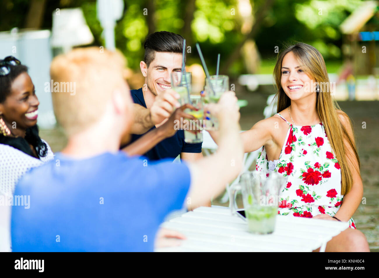Group of cheerful happy people toasting while sitting at a table Stock ...