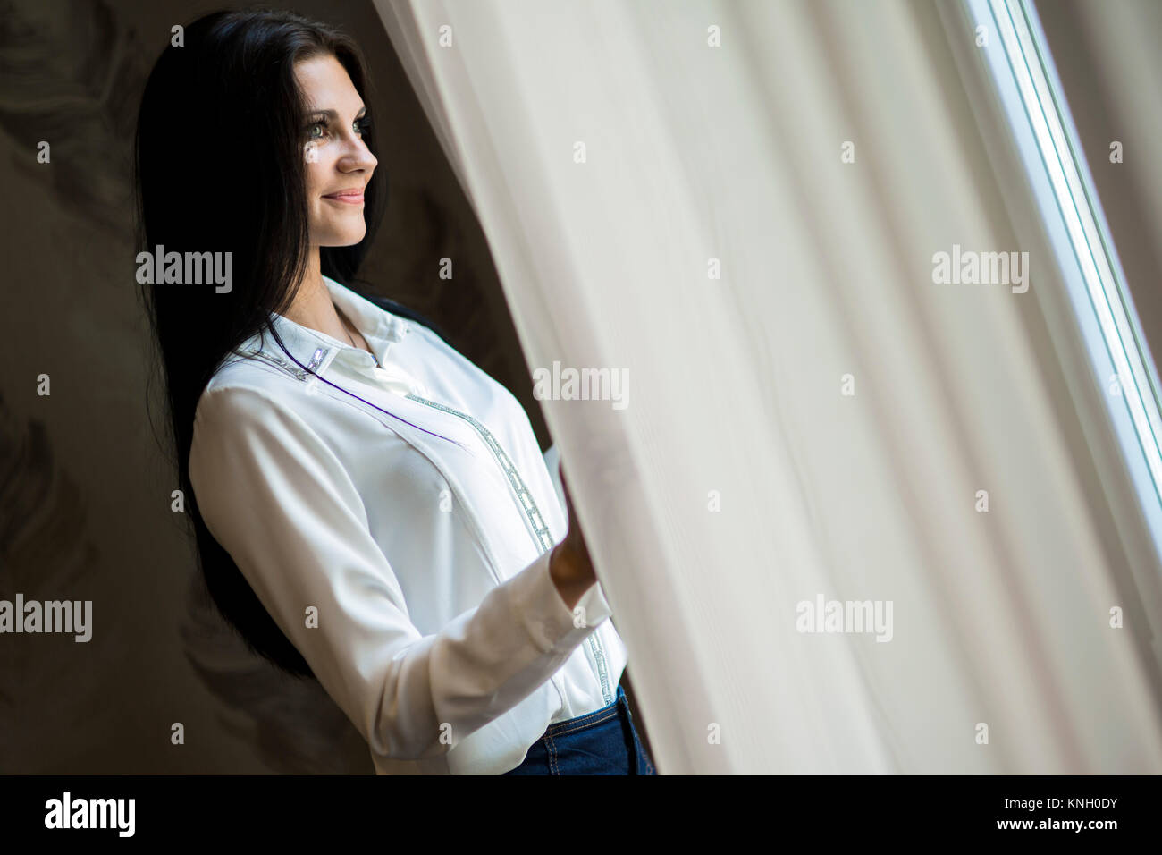 Happy beautiful woman staring out the window Stock Photo - Alamy