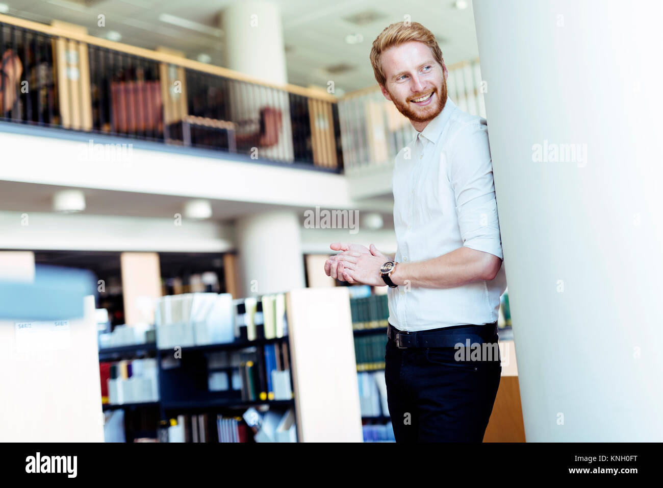 Handsome student smiling in library Stock Photo - Alamy