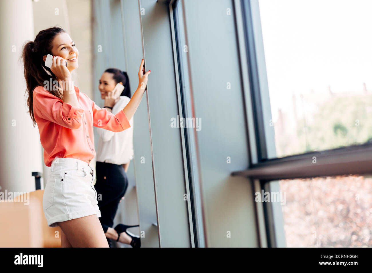 Beautiful women using phones and talkin during break Stock Photo - Alamy